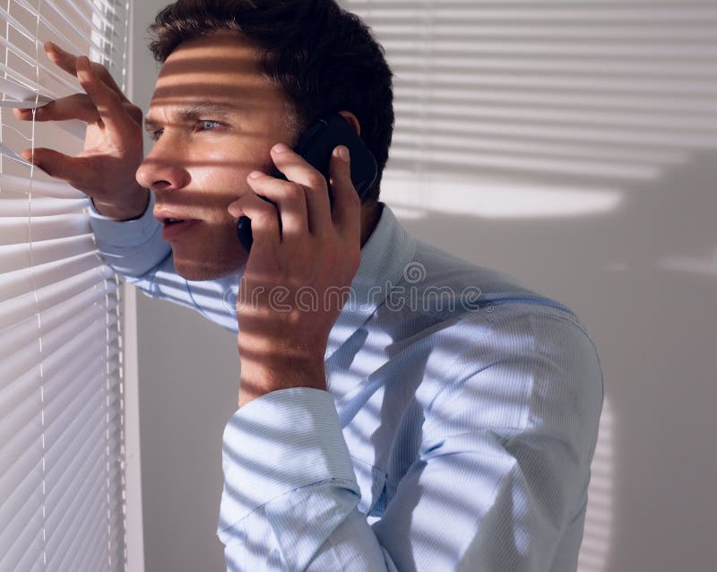 Businessman Peeking through Blinds while on Call in Office Stock Image ...