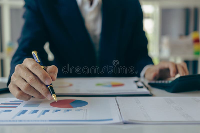 Businessman Points at Graph Charts and Uses Laptop Computer for Data ...