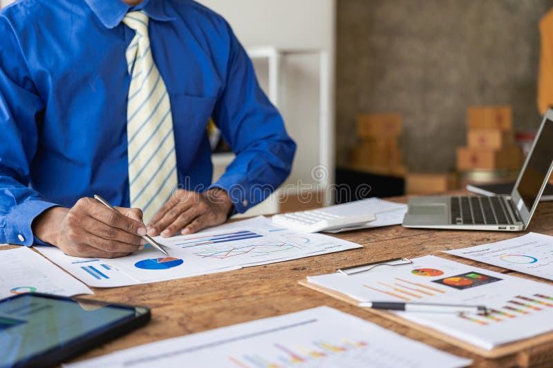 Businessman Points at Graph Charts and Uses Laptop Computer for Data ...