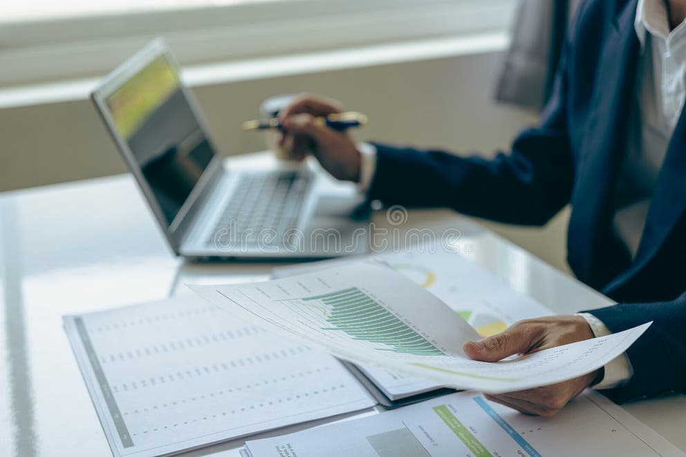 Businessman Points at Graph Charts and Uses Laptop Computer for Data ...