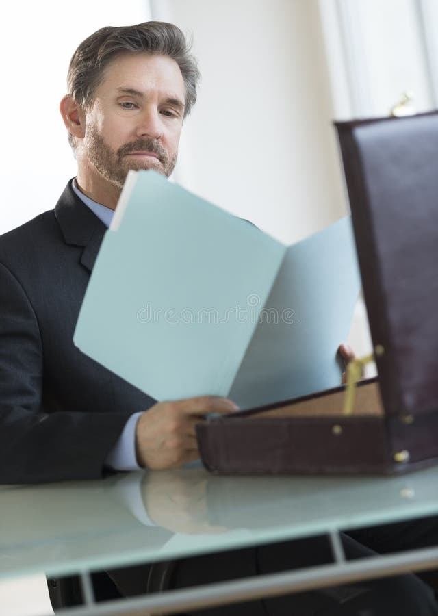 Businessman Reading Notes in File at Desk Stock Image - Image of ...