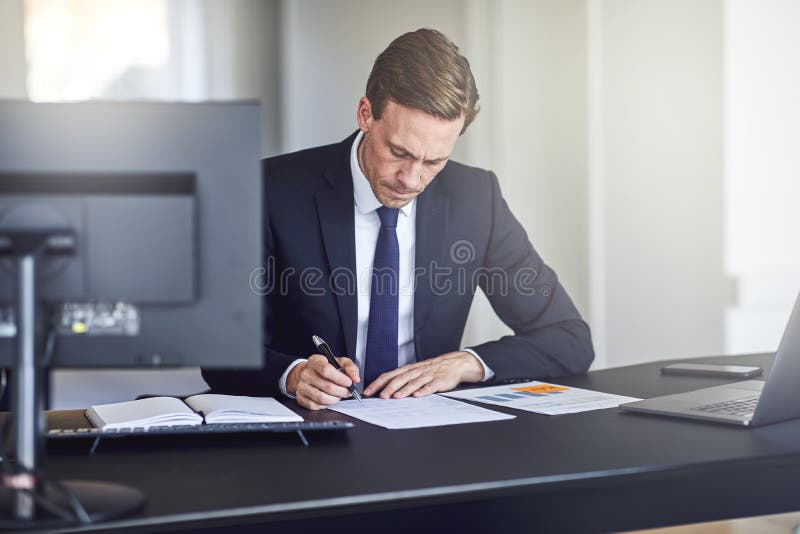 Businessman Reading through Paperwork at His Office Desk Stock Image ...