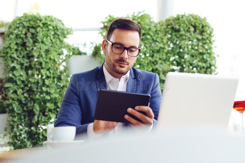 Businessman Relaxing at the Bar and Having a Coffee Break, he is Using ...
