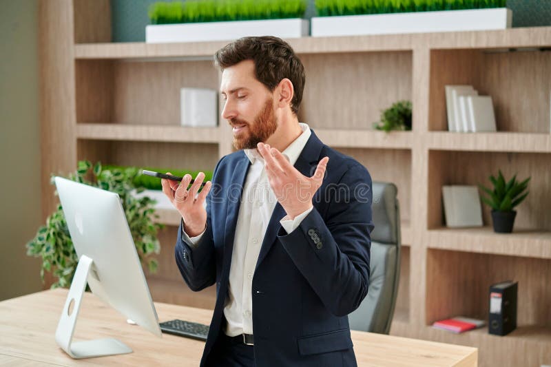 Businessman Seated at Workplace Desk Holding Smart Phone Speaking ...