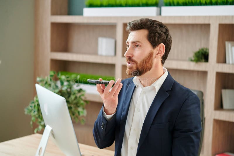 Businessman Seated at Workplace Desk Holding Smart Phone Speaking ...