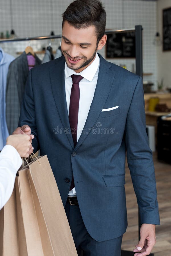 Partial View of Seller Giving Shopping Bags To Smiling Businessman ... Partial View of Seller Giving Shopping Bags To Smiling Businessman ...
