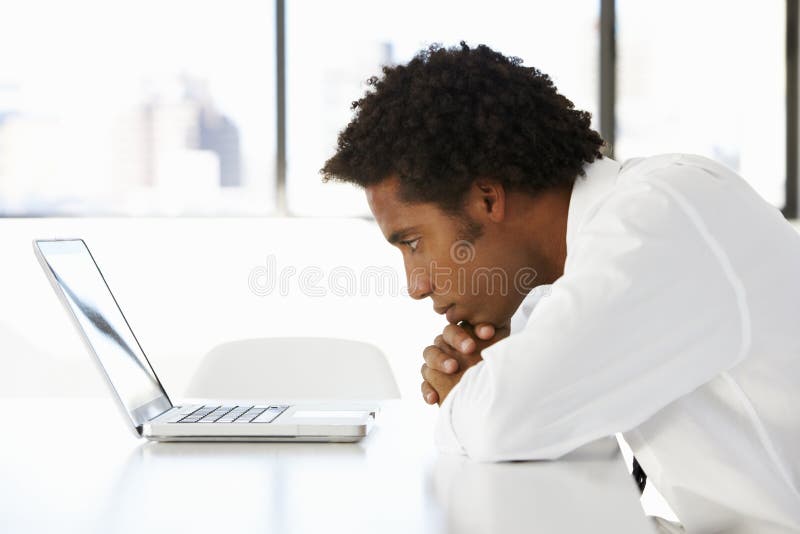 Businessman Sitting at Desk in Office Staring at Laptop Stock Photo ...