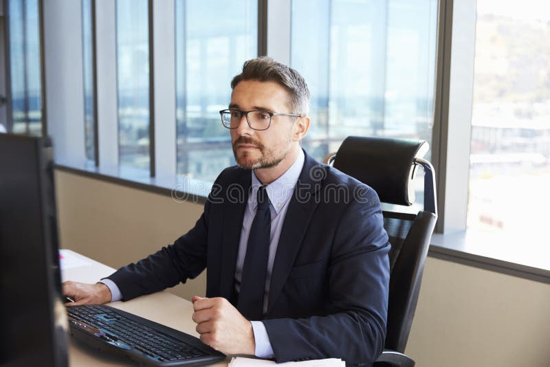 Businessman Sitting at Desk in Office Using Computer Stock Photo ...