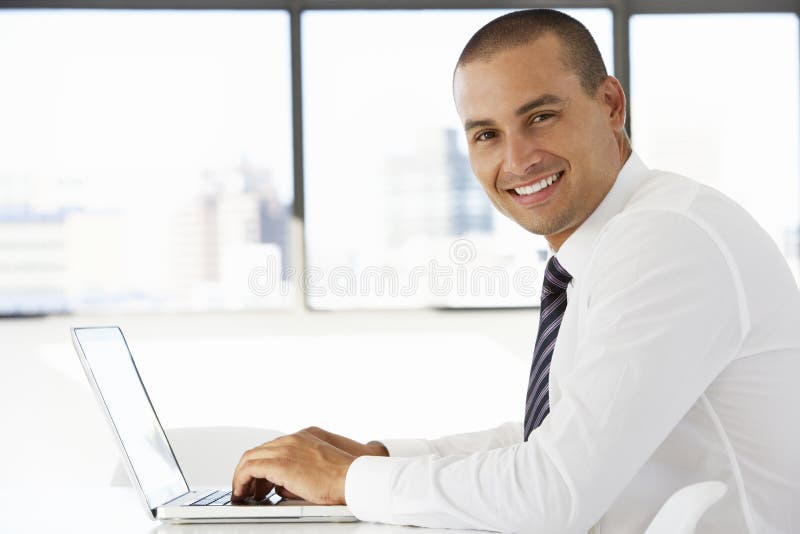 Businessman Sitting at Desk in Office Using Laptop Stock Photo - Image ...