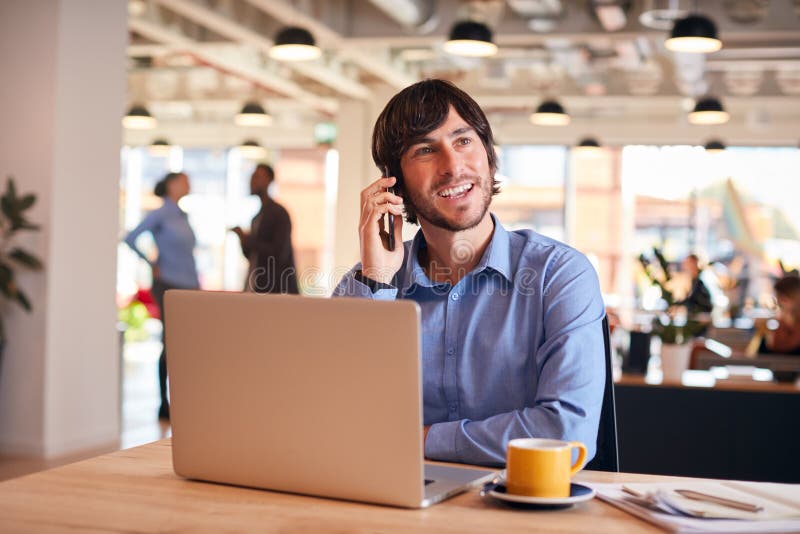 Businessman Sitting at Desk on Phone Call in Modern Open Plan Office ...