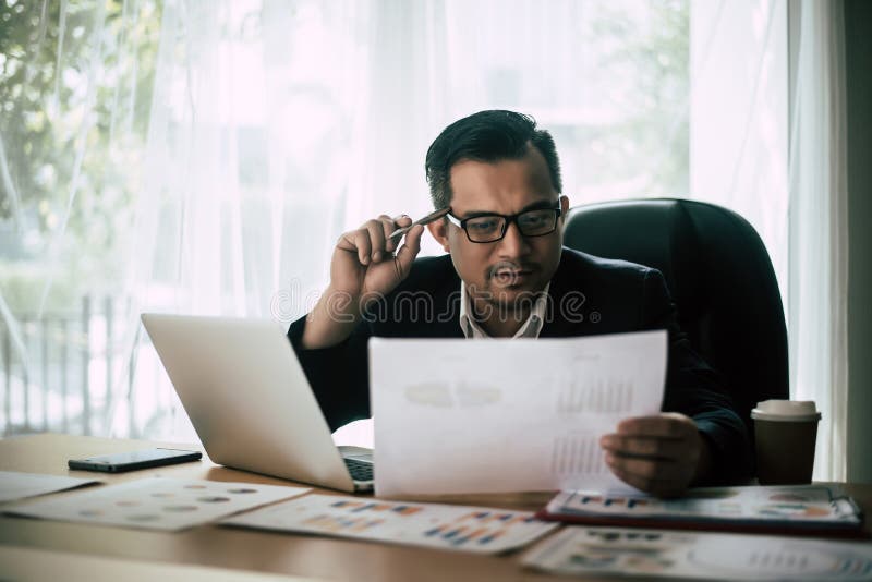Businessman Sitting at His Workplace in Front of Laptop Computer while ...