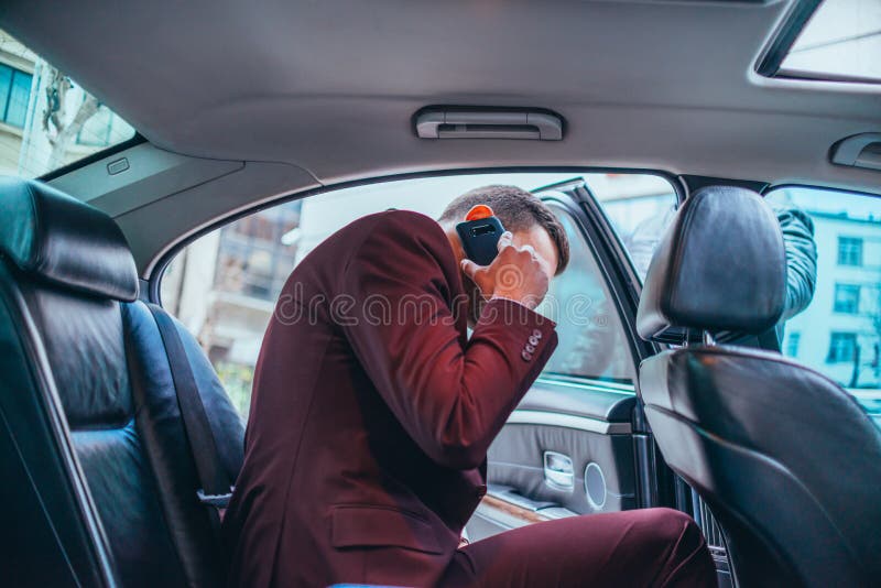 Businessman Sitting in a Limo while Talking on His Phone Reading His ...