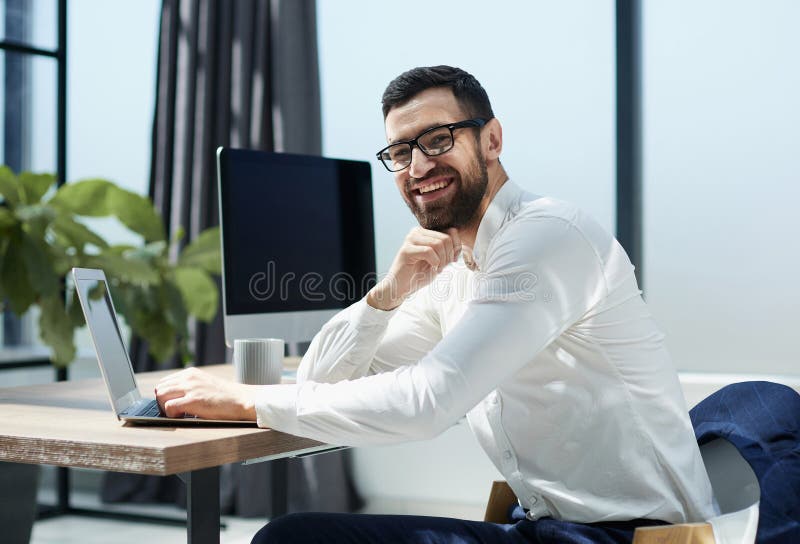 Businessman Sitting at Office Desk Working on Laptop Computer Stock ...