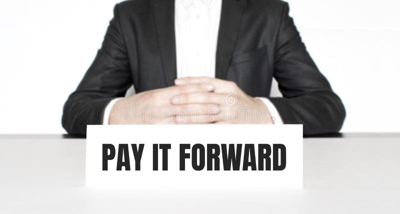 Businessman Sitting at the Table and Signboard with Text PAY it FORWARD ...