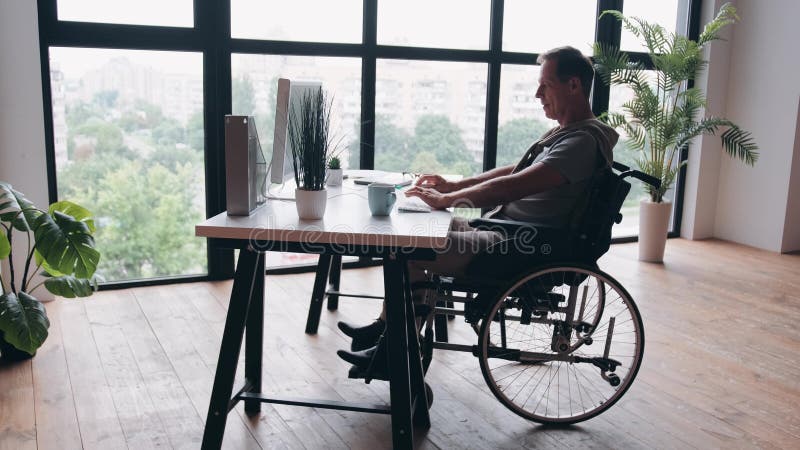 Businessman Sitting in Wheelchair Using Computer at Workplace Stock Photo - Image of tall, tech ...