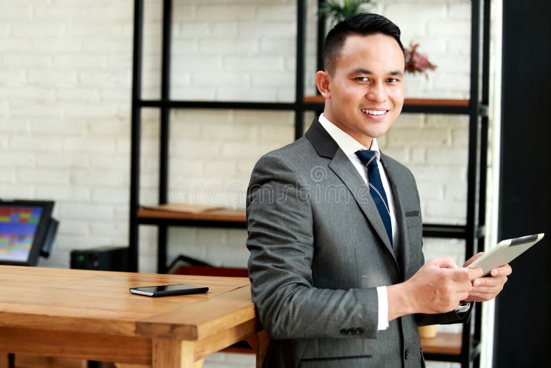 Businessman Smiling and Holding a Tablet while Lean Back at Table Stock ...