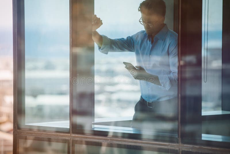 Businessman Standing Inside Office Building and Using Smartphone Stock ...
