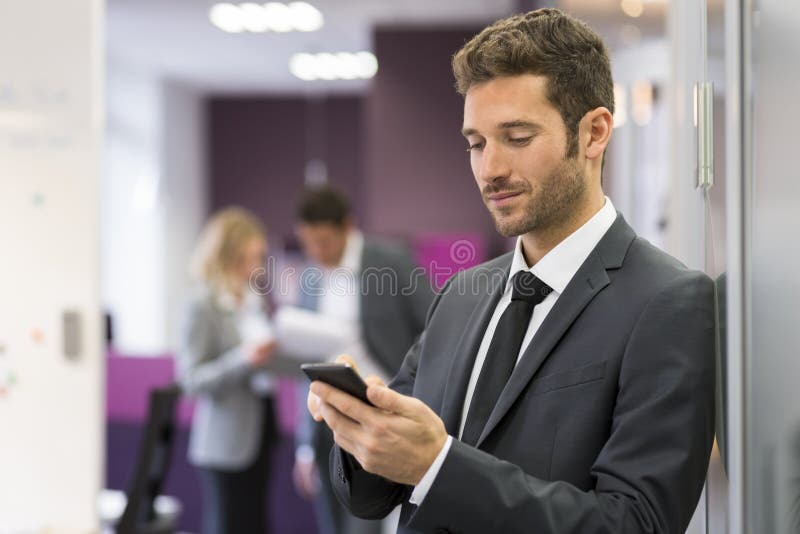 Businessman Typing a Message on Smart-phone in Modern Office Stock ...