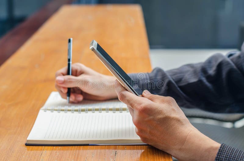 Businessman Use Smartphone while Making Notes in Notebook. Student ...
