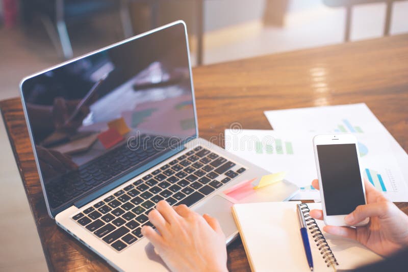 Businessman Uses a Phone To Work on Charts and Graphs that Show Stock ...