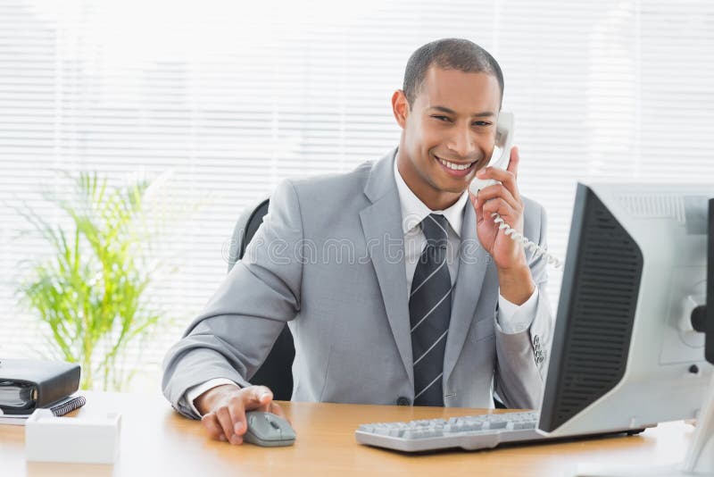Businessman Using Computer and Phone at Office Desk Stock Photo - Image ...
