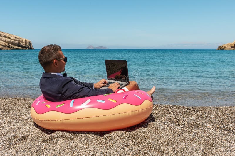 Businessman Using Laptop Computer on Inflatable Donut on Tropical Beach ...
