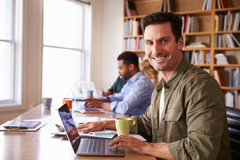 Businessman Using Laptop at Desk in Busy Office Stock Image - Image of ...