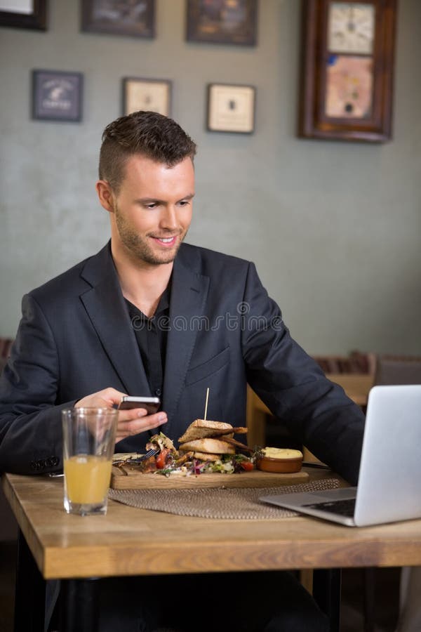 Businessman Using Laptop while Having Food in Stock Photo - Image of ...