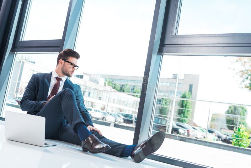 Handsome Young Businessman Sitting on Floor and Looking at Window while ...
