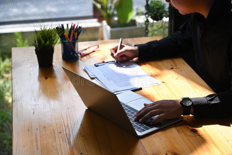 Businessman Using Laptop and Writing on Business Documents. Stock Photo ...