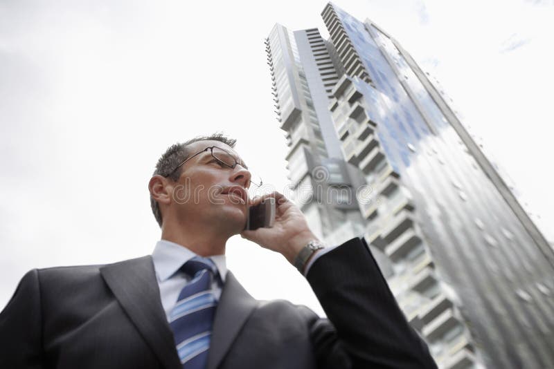 Businessman Using Mobile Phone Against Tall Building Stock Photo ...