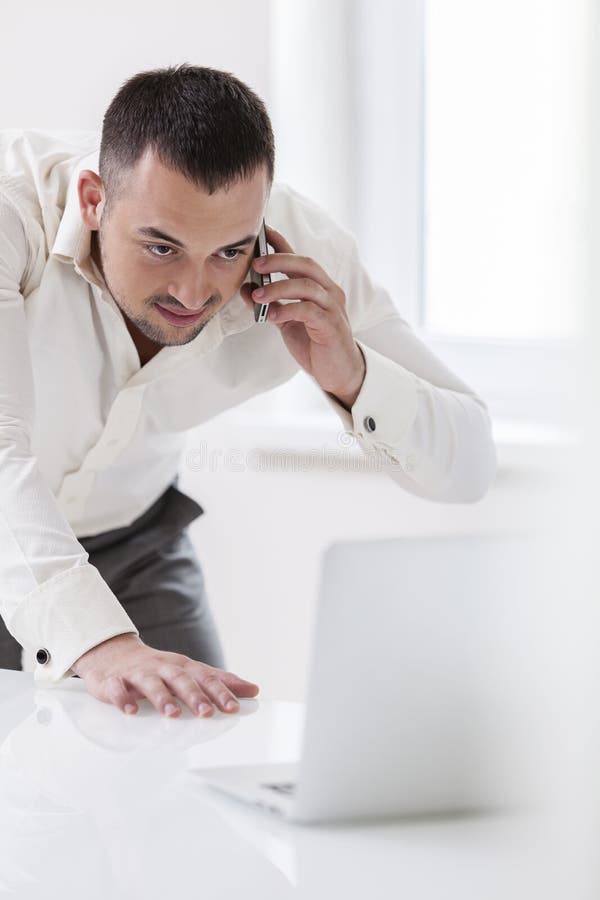 Businessman Using Mobile Phone and Looking at Computer Stock Image ...