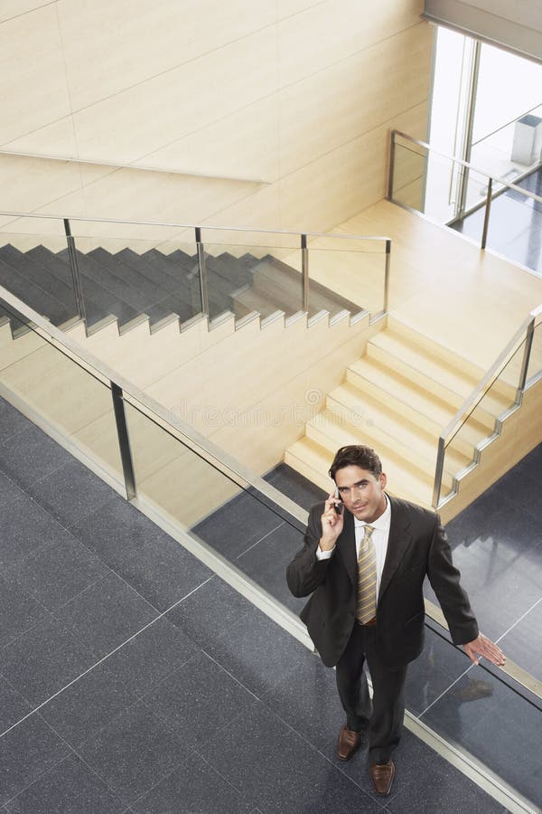 Businessman Using Mobile Phone while Standing by Glass Railing Stock ...