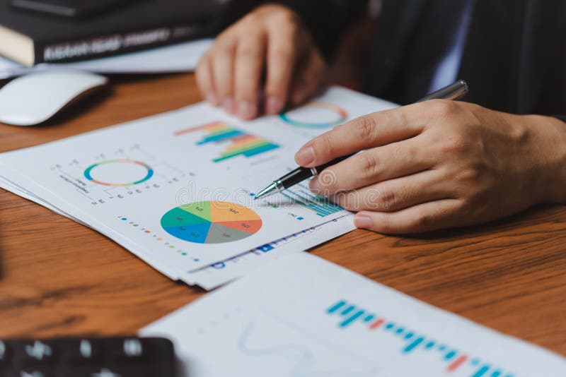 Businessman Using a Pen To Mark Charts and Data Analyzing Documents and ...