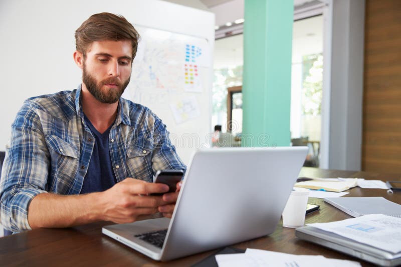 Businessman Using Phone Working on Laptop in Office Stock Image - Image ...