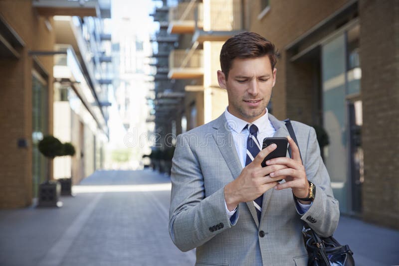 Businessman Walking To Work in City Looking at Mobile Phone Stock Photo ...