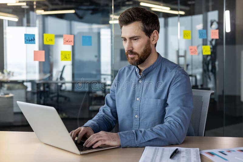 Focused Businessman Working on Laptop in Modern Office with Glass ...