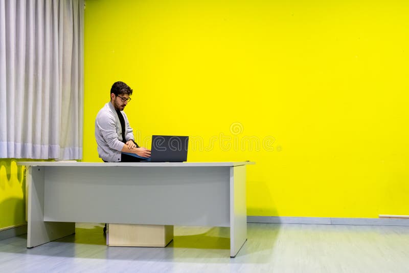 Businessman Working on Laptop in Yellow Office with Minimalist Desk ...