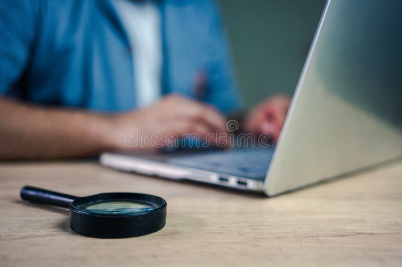 A Businessman Works on a Computer with a Magnifying Glass on Table ...