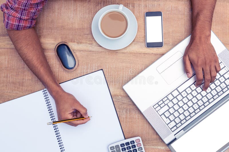 Businessman Writing on Book while Working on Laptop Stock Image - Image ...
