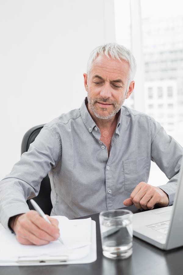 Businessman Writing Notes while Using Laptop at Office Desk Stock Image ...