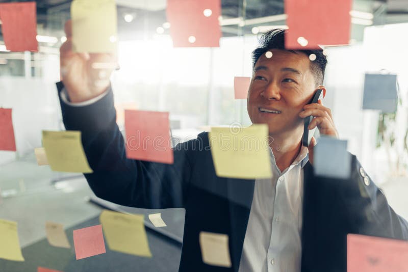 Businessman Writing on Sticky Notes on Glass Wall while Working in ...