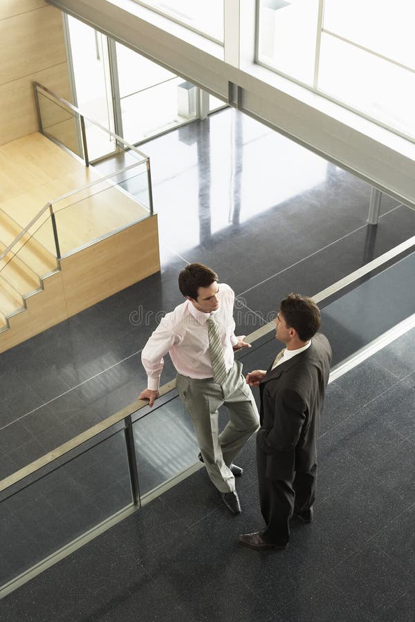 Businessmen Conversing by Railing in Office Stock Photo - Image of ...