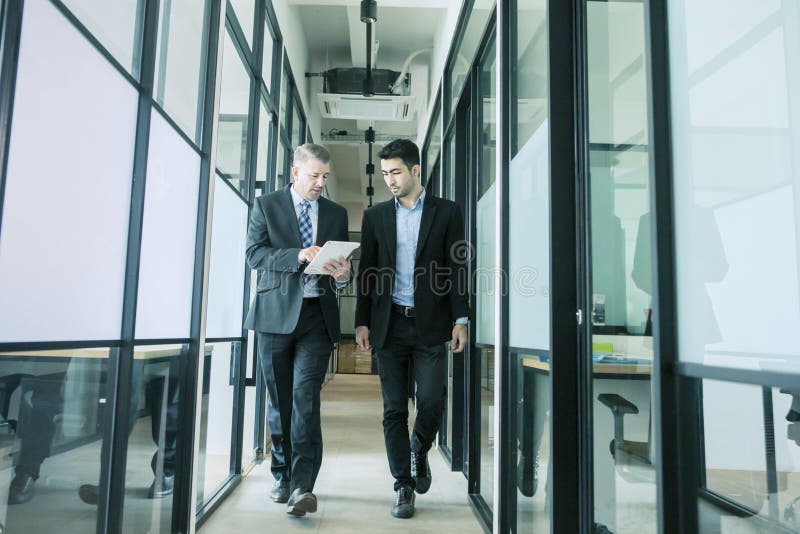 Businessmen Discussing Work while Walking in Office Corridor Stock ...