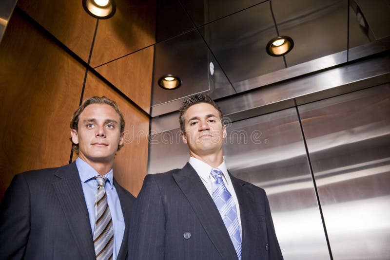 Businessmen Riding in Elevator Stock Photo - Image of years, standing ...
