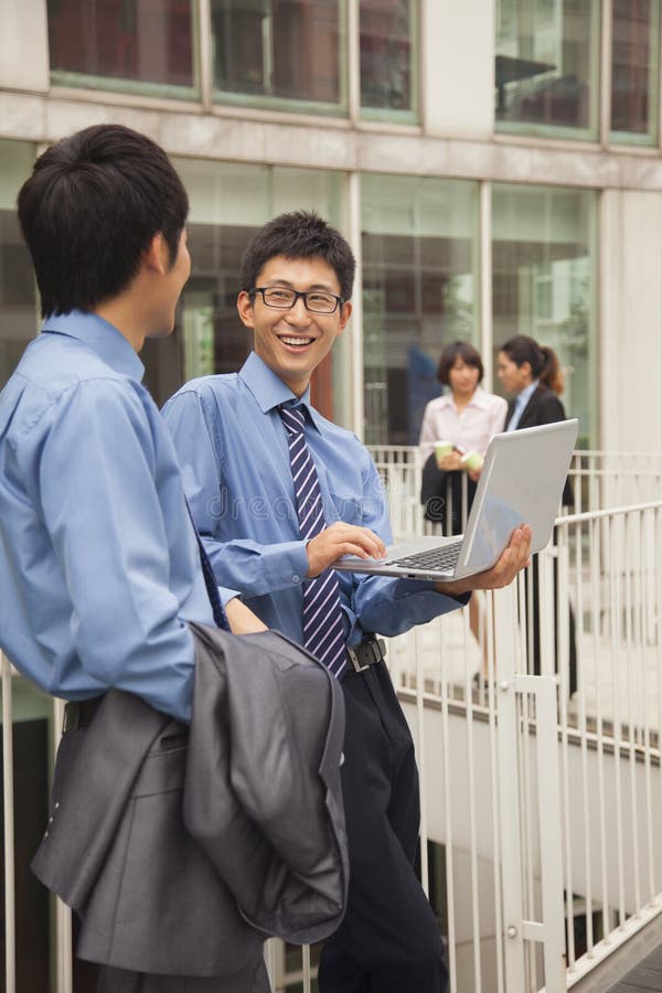 Businessmen Smiling and Working Together Outside with Laptop Stock ...