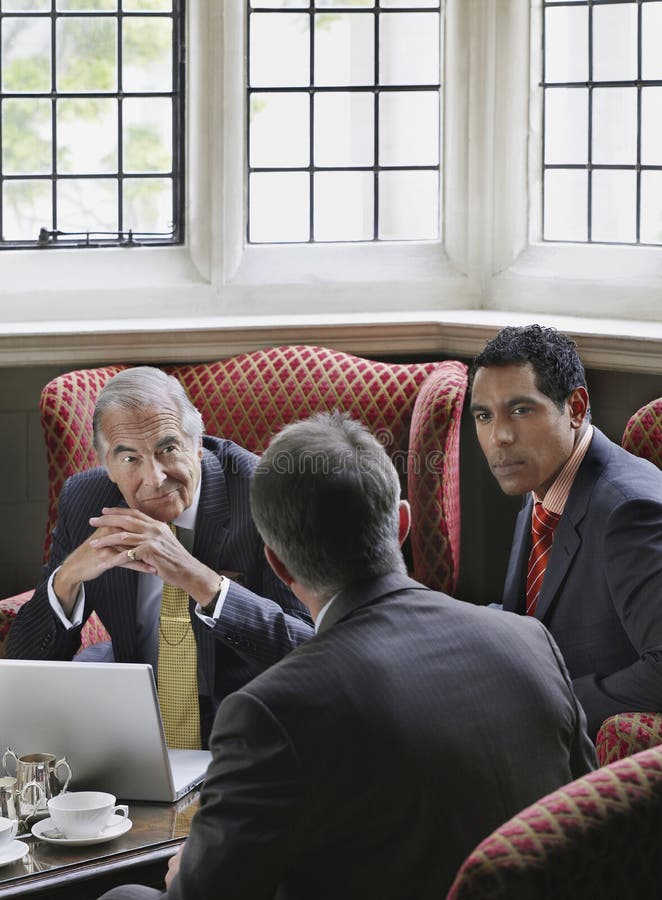 Businessmen Talking Over Laptop in Lobby Stock Photo - Image of black ...