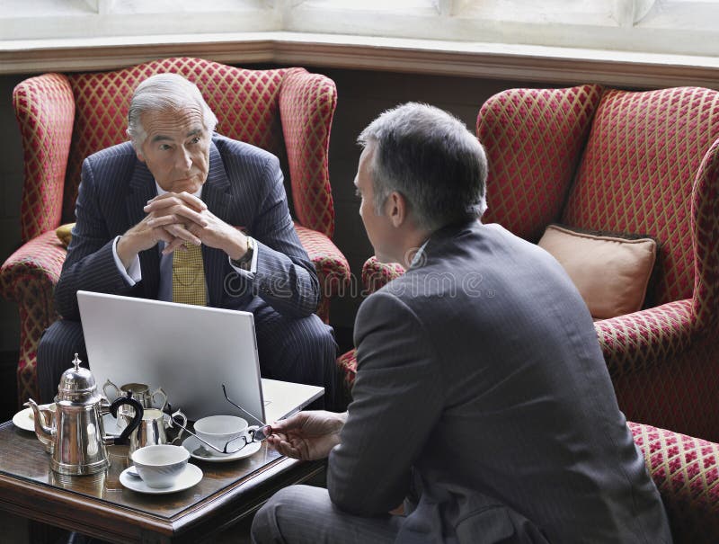 Businessmen Talking Over Laptop in Lobby Stock Photo - Image of ...
