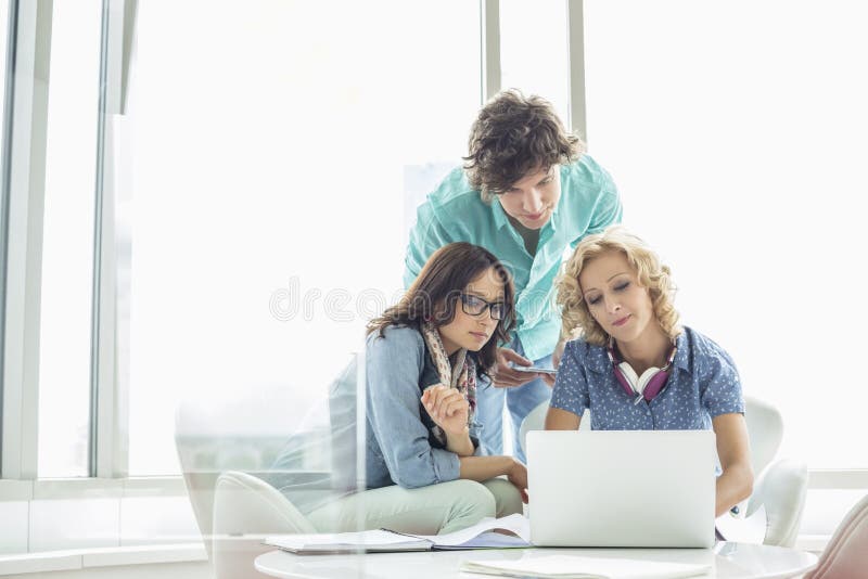 Businesspeople Using Laptop at Table in Creative Office Stock Image ...