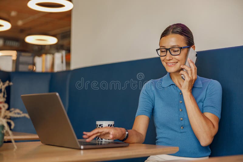 A Businesswoman on a Call while Using Her Laptop in a Modern Workspace ...